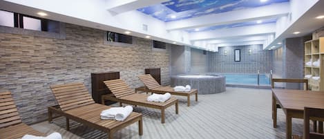 Uma área de spa com espreguiçadeiras de madeira, hidromassagem e parede de pedra.