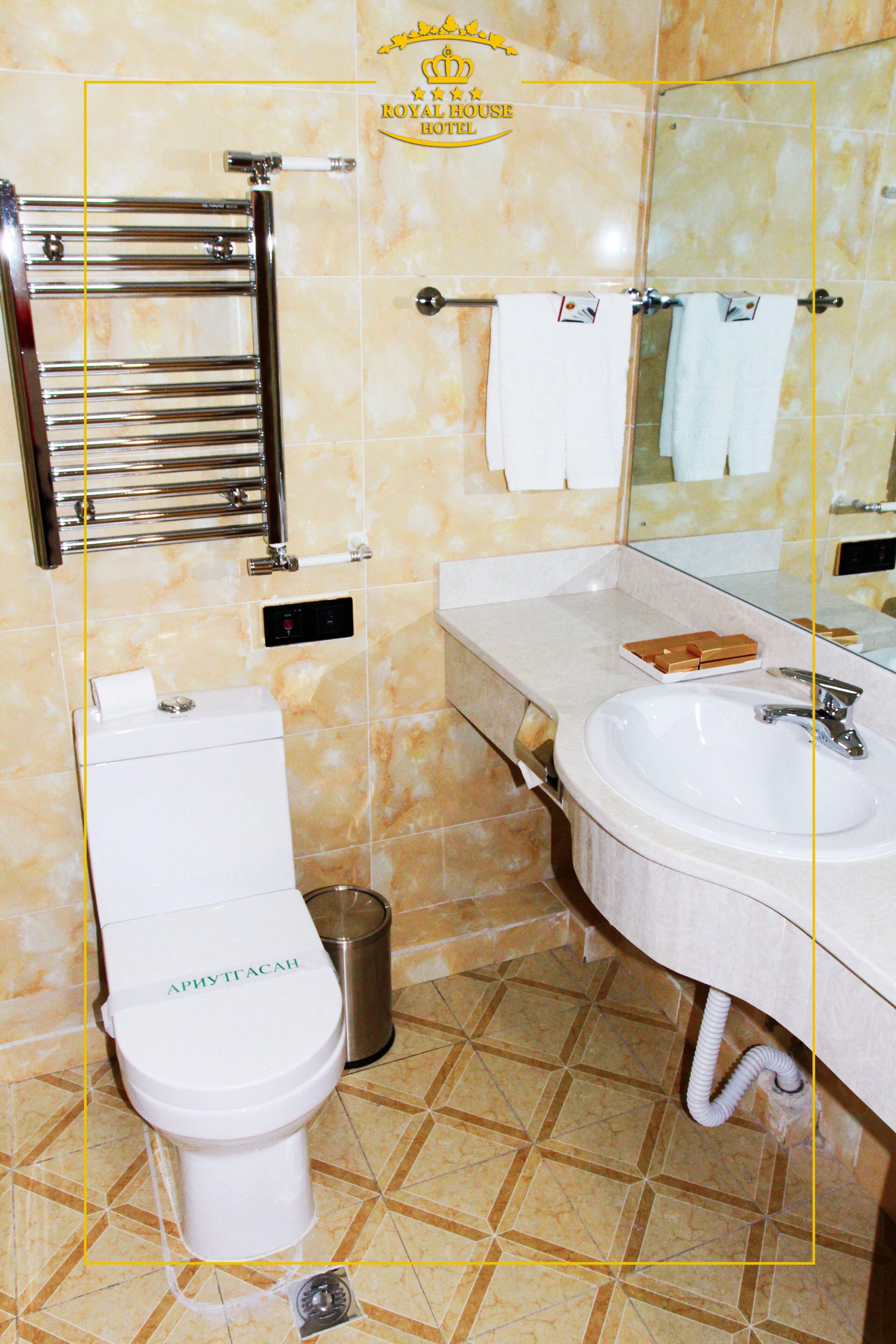 Casa de banho com sanita, lavatório e suporte para toalhas.