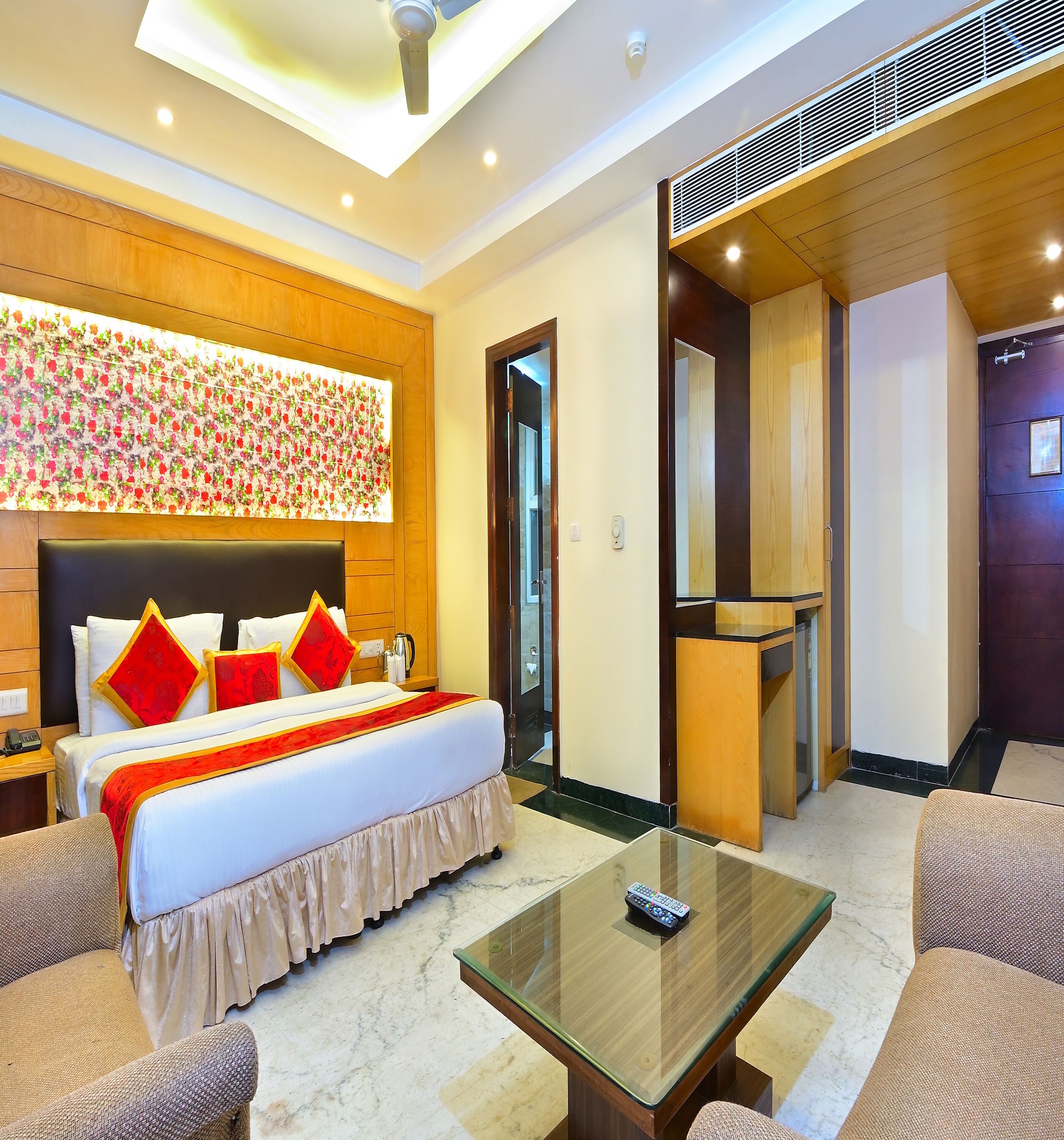 Quarto de hotel com uma cama grande, uma mesa de centro de vidro e uma área de estar com dois sofás.