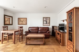 Uma sala de estar com sofá de couro marrom, mesa de centro de madeira e um aparador para TV.