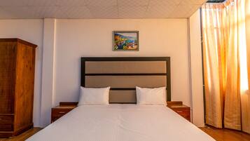 Quarto bem arrumado com uma cama grande, guarda-roupa de madeira e um quadro na parede.