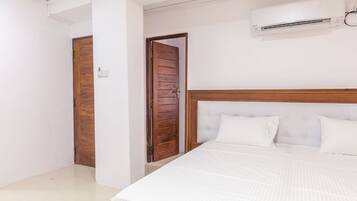 Quarto com cama, porta de madeira e ar condicionado.