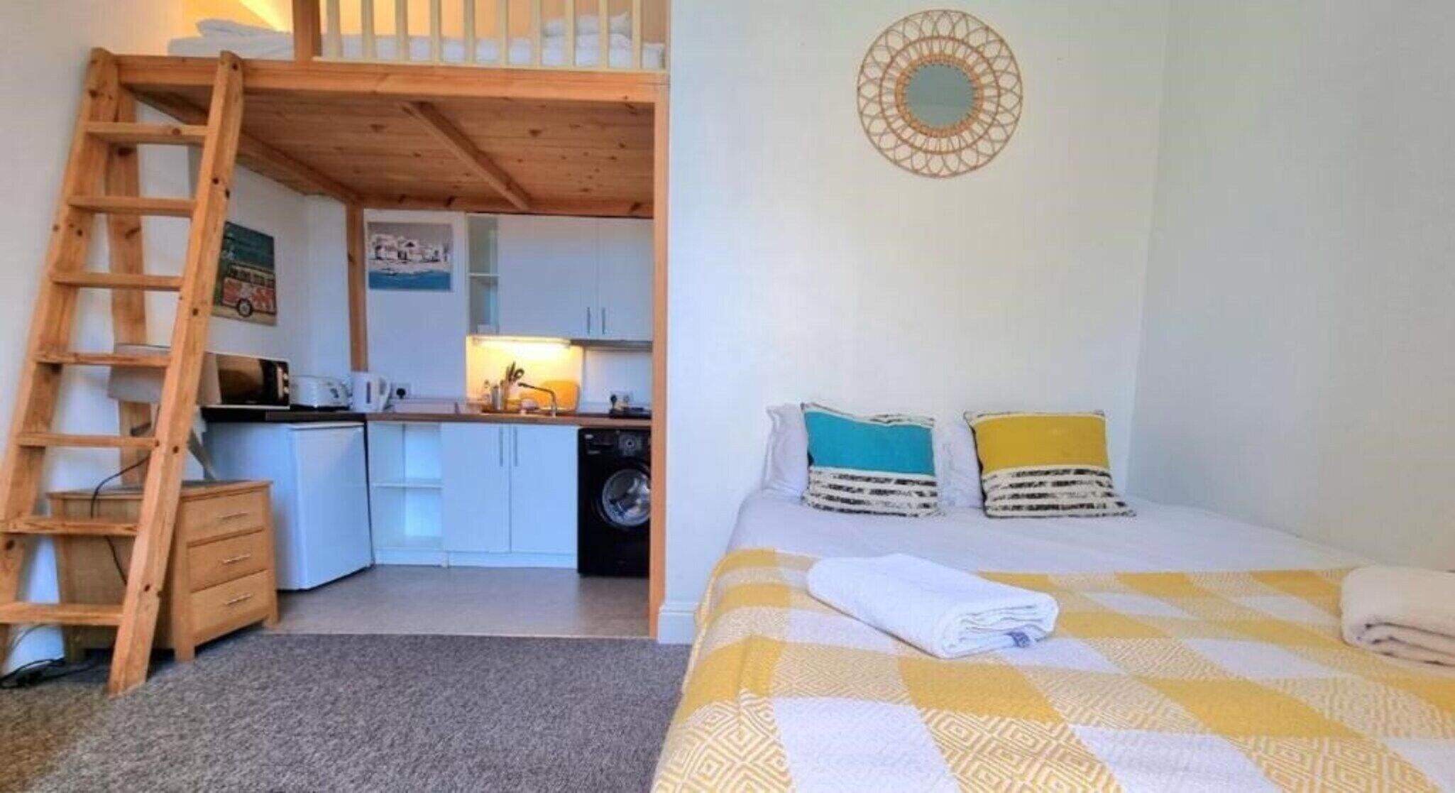Quarto compacto com beliche, pequeno espaço de cozinha e máquina de lavar.