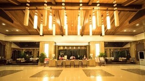 Um saguão de hotel com balcão de recepção, área de estar e um grande candelabro.
