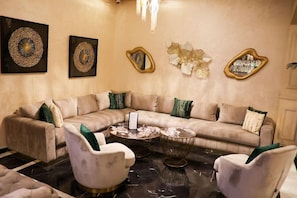 Uma sala de estar moderna com um sofá seccional bege, duas poltronas, uma mesa de centro e arte decorativa na parede.