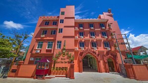 Um edifício cor-de-rosa com várias janelas e uma ampla entrada em arco.