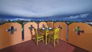 Varanda com mesa e cadeiras, vista para a cidade iluminada à noite.