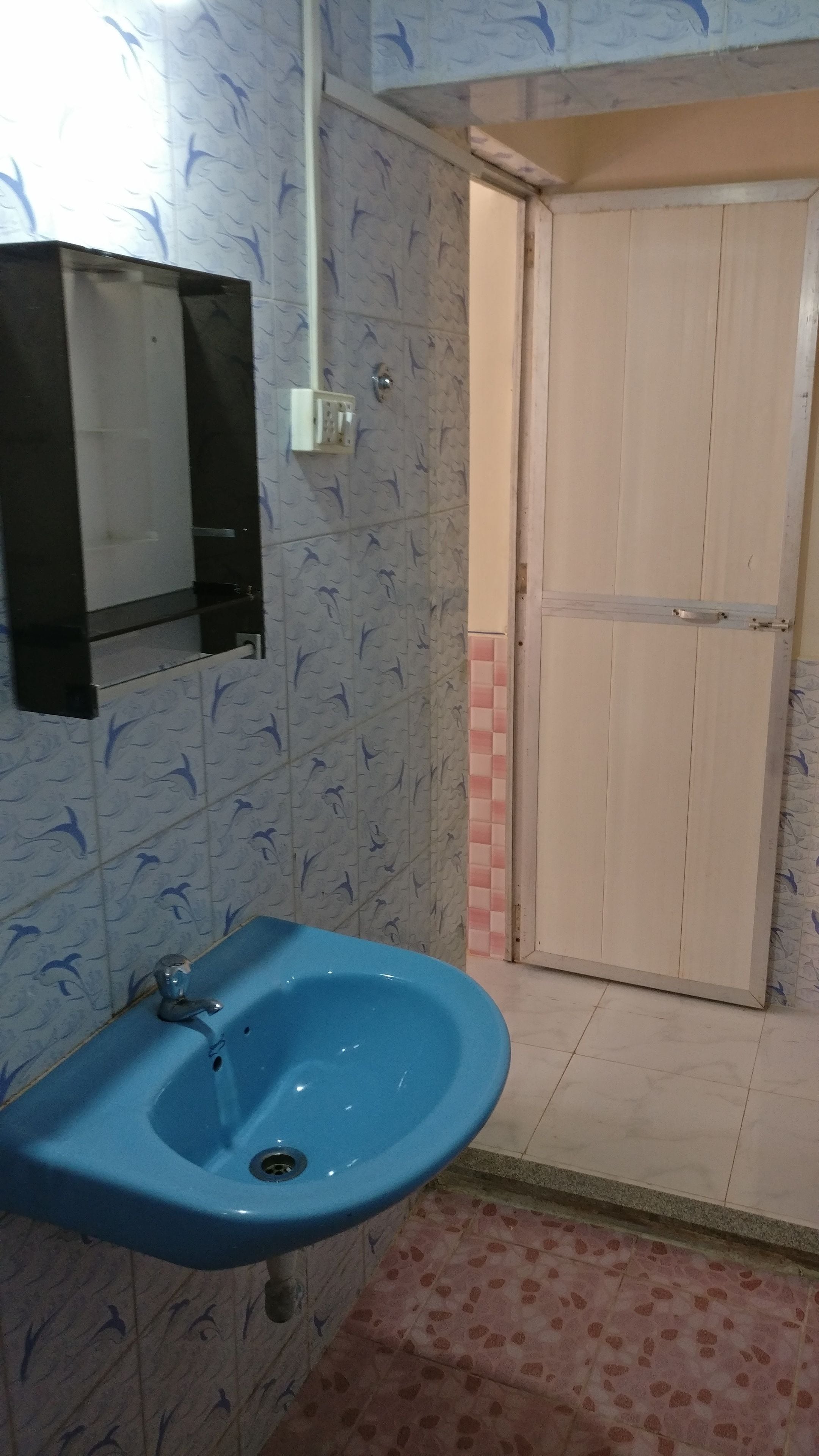 Uma casa de banho com uma pia azul, um espelho e uma porta.