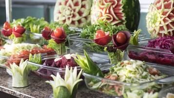 Buffet com diversas saladas e frutas entalhadas.