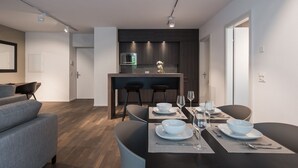 Uma sala de estar moderna com área de jantar, cozinha com armários escuros e uma ilha central.