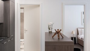 Cozinha moderna com armários de madeira escura, uma ilha central e vista para o quarto adjacente.