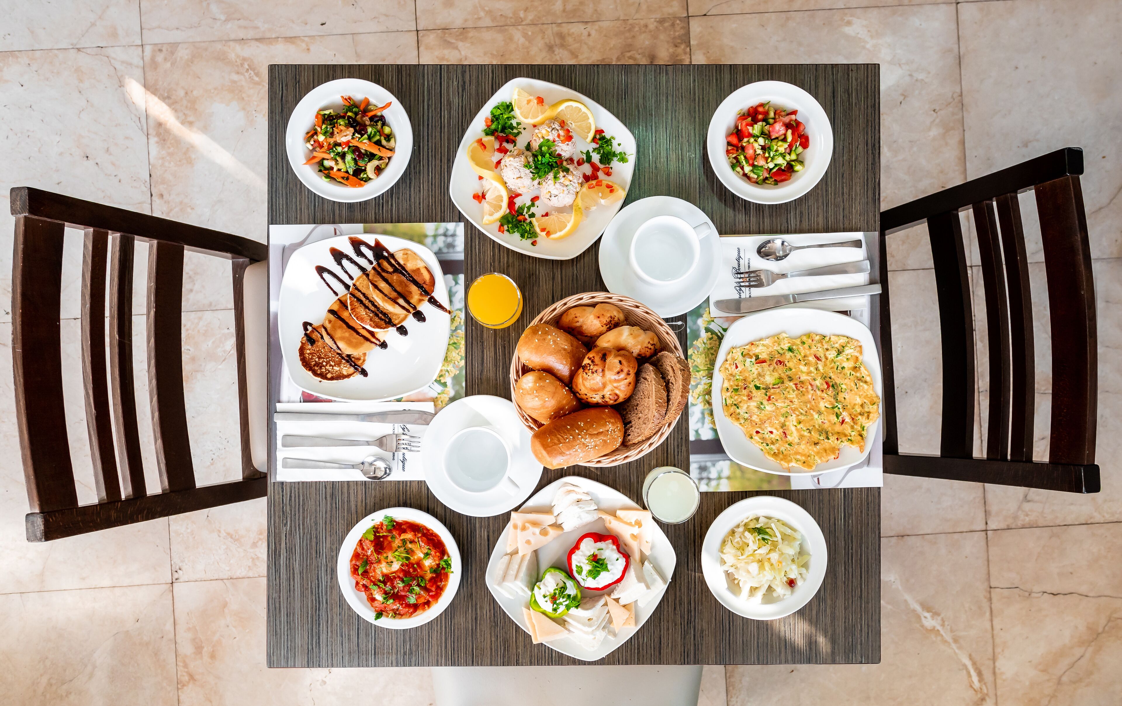 Uma mesa de jantar com diversos pratos, incluindo panquecas, uma salada e uma tigela de sopa.