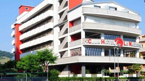 Um hotel com vários andares, varandas, fachada em vermelho e branco, e uma placa com a inscrição 'Club Hotel Le Nazzioni'.
