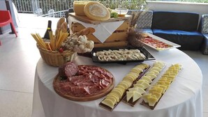 Mesa de buffet com diversos alimentos, incluindo carnes, queijos e pão.