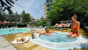 Uma área de piscina com espreguiçadeiras e uma banheira de hidromassagem.