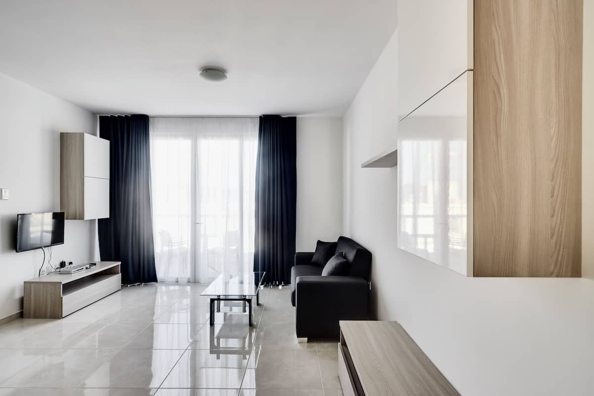 Uma sala de estar moderna com televisão de tela plana, sofá, mesa de centro e um armário de madeira.
