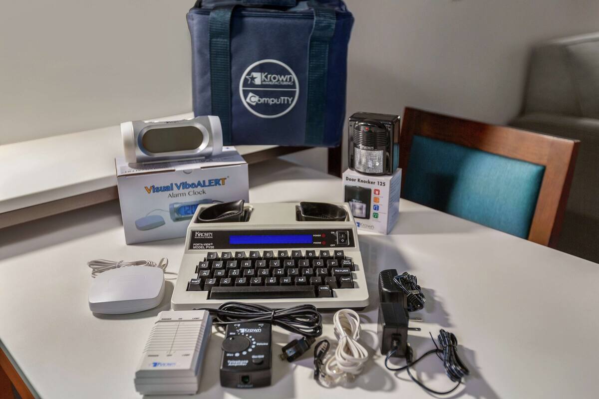 Uma mesa com teclado, mouse, microfone e uma bolsa com a etiqueta 'Krown CompUty'.
