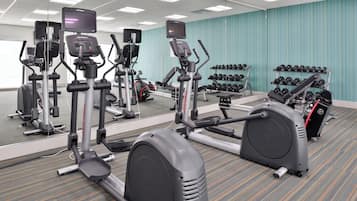 Academia com diversos equipamentos de exercício, incluindo esteiras, elípticos e máquinas de musculação.