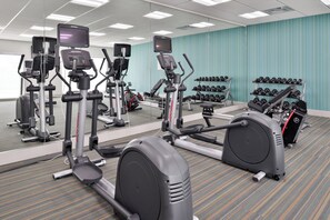 Academia com diversos equipamentos de exercício, incluindo esteiras, elípticos e máquinas de musculação.