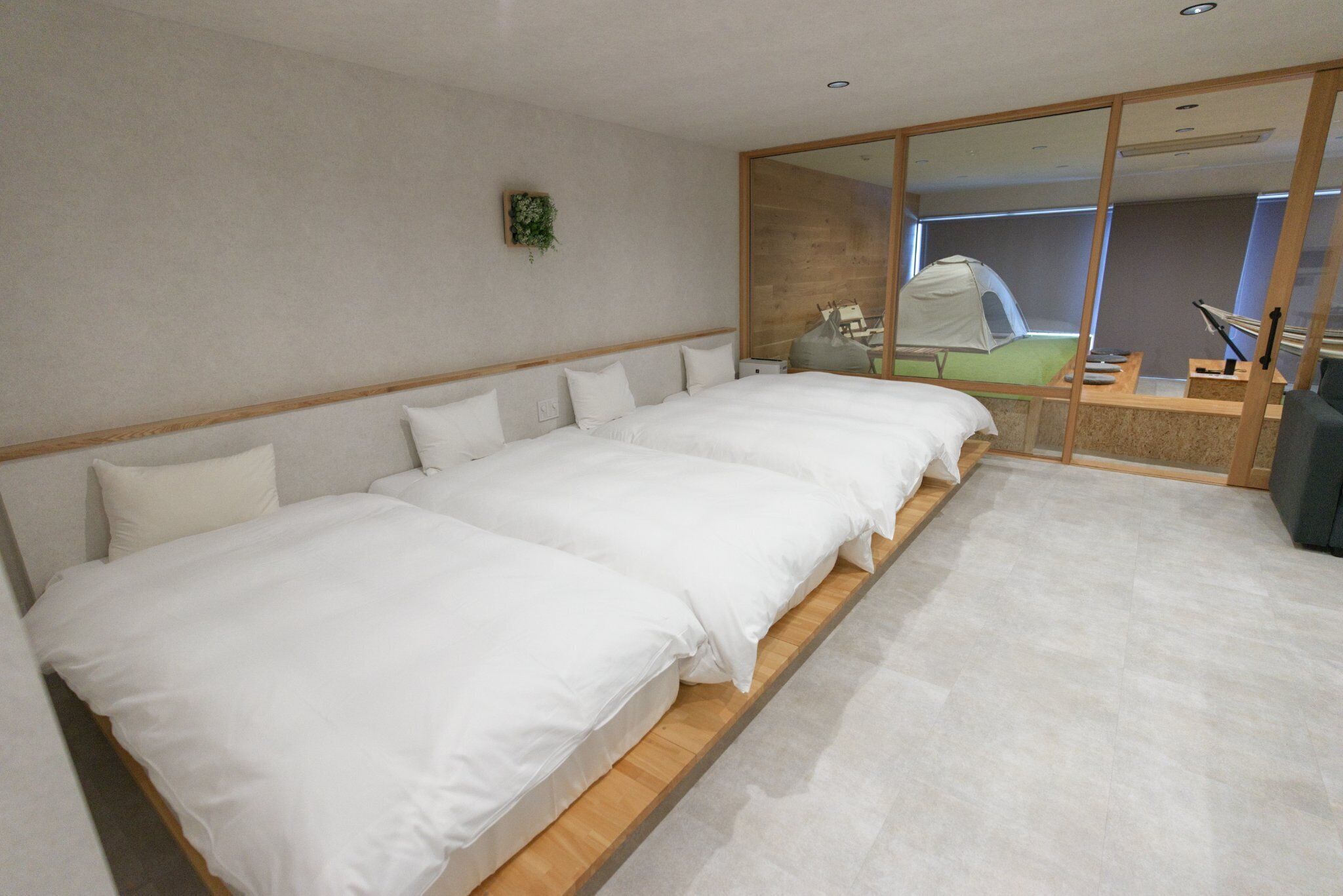 Quarto de hotel moderno com uma cama grande, cabeceira de madeira, uma mesinha de cabeceira pequena e um espelho com porta deslizante.