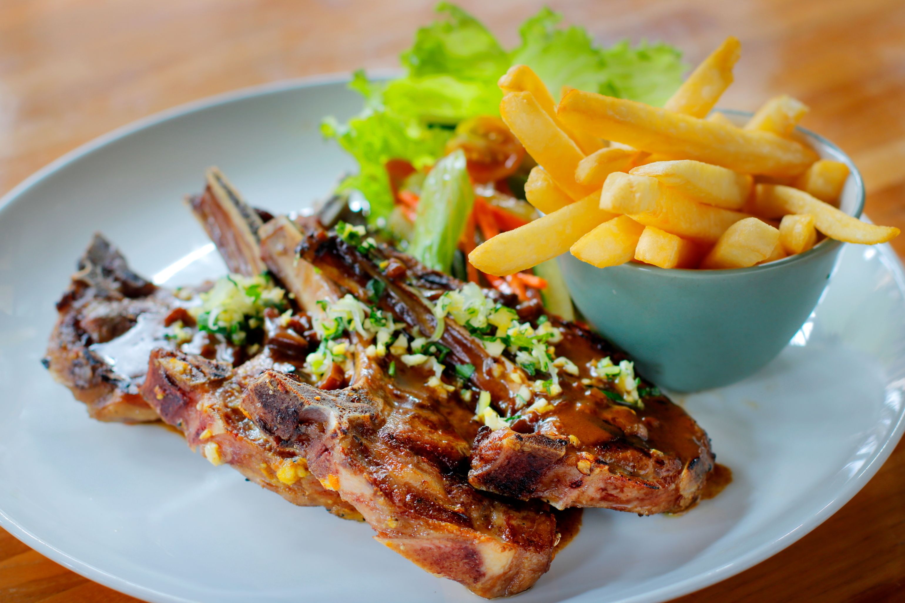 Um prato com carne grelhada, batatas fritas e uma salada.