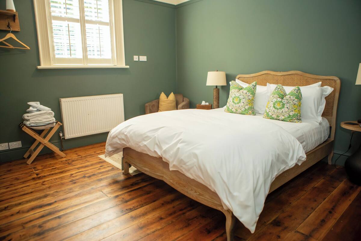 Um quarto com uma cama de madeira, um radiador, uma janela e uma cadeira.