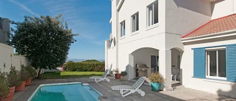 Uma casa de dois andares com piscina, área de estar externa e jardim.