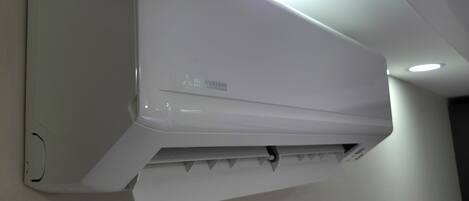 Unidade de ar condicionado branca fixada na parede, com o logotipo da Mitsubishi.