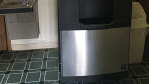 Uma geladeira de aço inoxidável com dispensador de água e pequeno compartimento para gelo.