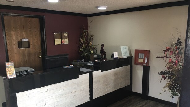 Balcão de recepção com design preto e branco, porta de madeira e um mural de avisos.
