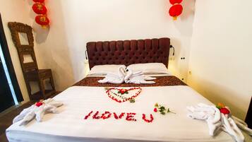 Cama bem arrumada com arranjo de flores em formato de coração, onde a palavra 'LOVE' está escrita com pétalas vermelhas.