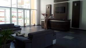 Uma área de recepção moderna com sofá, balcão de atendimento e uma grande janela com vista para o exterior.
