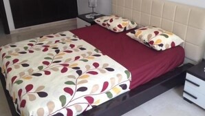 Um quarto com cama, mesa de cabeceira e cômoda.