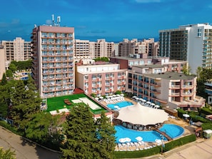 Hotel com vários andares, piscina no terraço e área ajardinada com espreguiçadeiras.