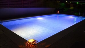 Uma piscina à noite com uma única vela iluminada na borda.