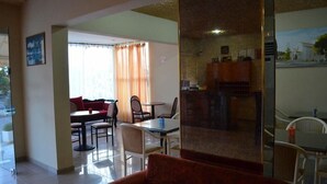 Uma área de refeições com mesa, cadeiras, um sofá e um painel de vidro.