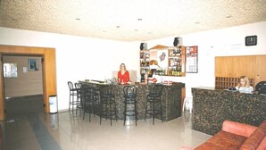 Um saguão de hotel com balcão de recepção, área de bar e assentos.
