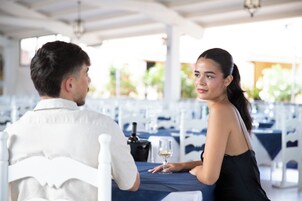 Um casal jantando à mesa com vista para um jardim.
