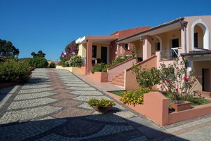 Um hotel com um caminho de paralelepípedos que leva a um edifício com escadas e varanda.