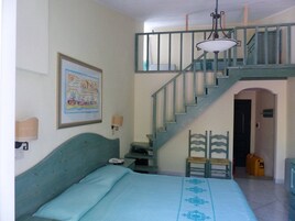 Quarto com cama, escada, cadeira, escrivaninha e luminária fixada na parede.