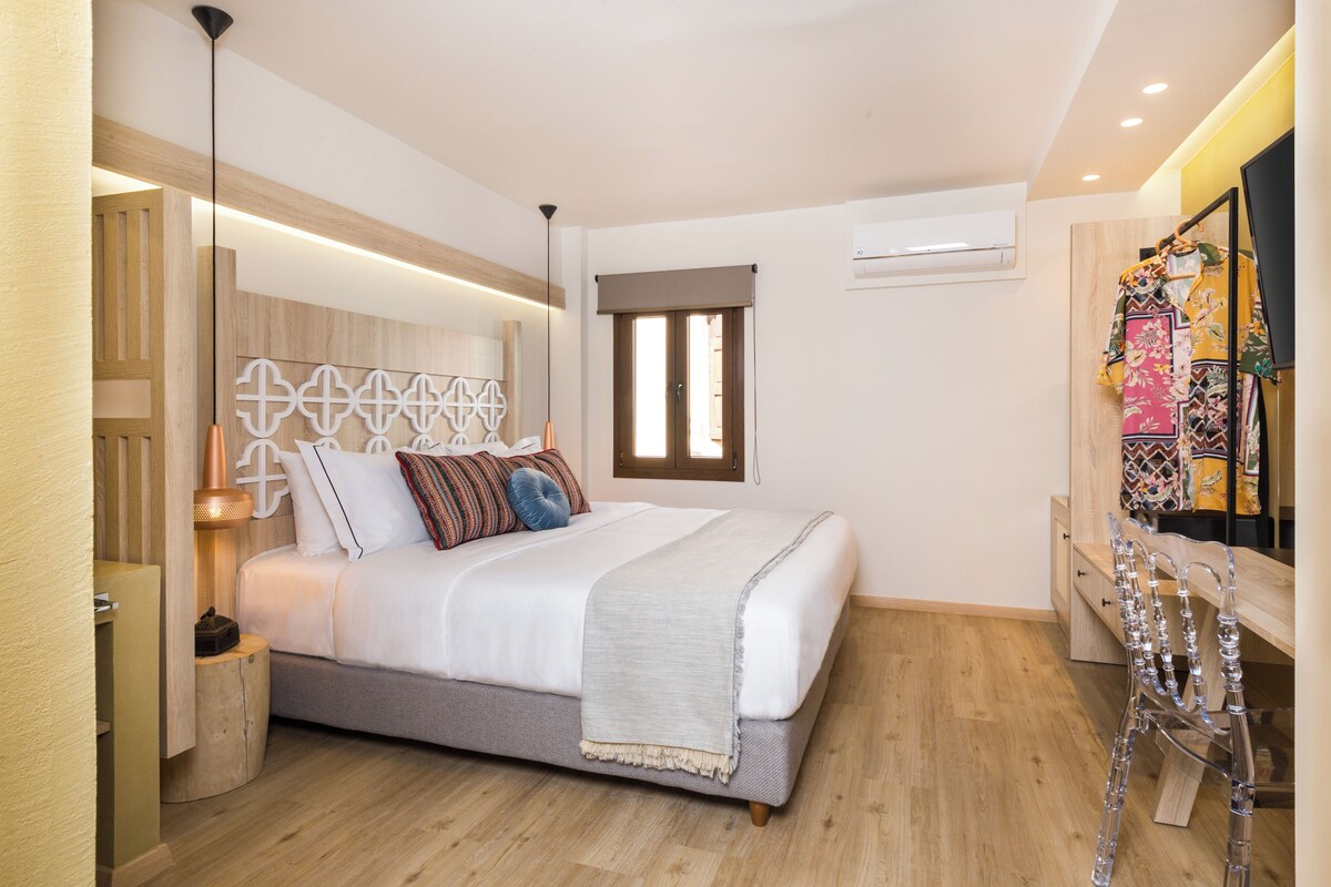 Um quarto moderno com cama, mesa de cabeceira, abajur e televisão na parede.