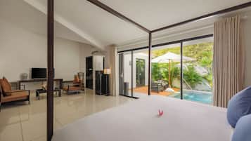 Quarto de hotel moderno com uma cama grande, televisão, área de refeições e vista para uma piscina ao ar livre.