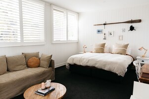 Um quarto com cama, sofá, mesa de centro e escrivaninha.