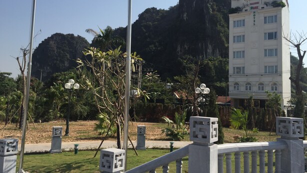 Um hotel com montanhas ao fundo, destacando um edifício com varanda e uma placa indicando "HALONG PARK HOTEL".