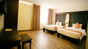 Quarto de hotel com duas camas, uma escrivaninha e uma televisão.