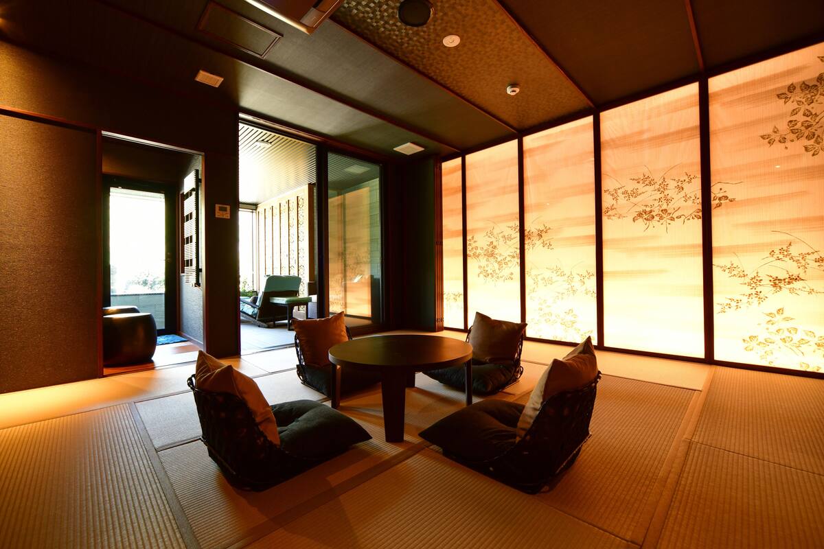 Um quarto japonês tradicional com tatames, uma mesa baixa e almofadas.