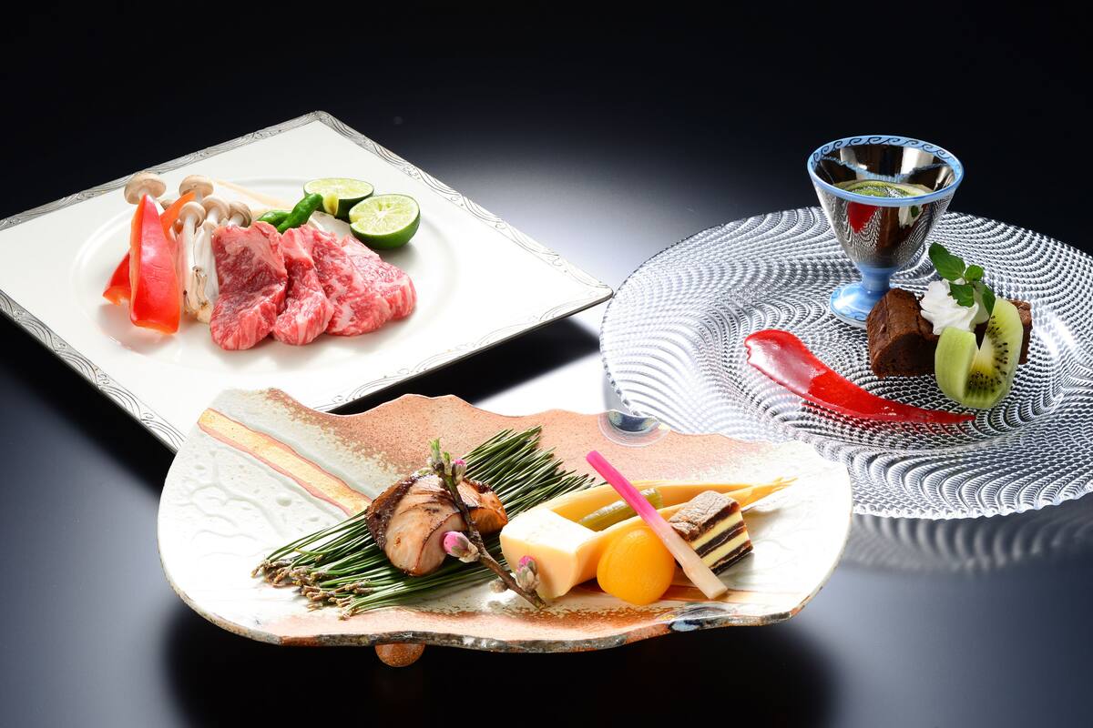 Uma mesa com dois pratos de comida: um com carne e legumes, e outro com queijo e fruta.