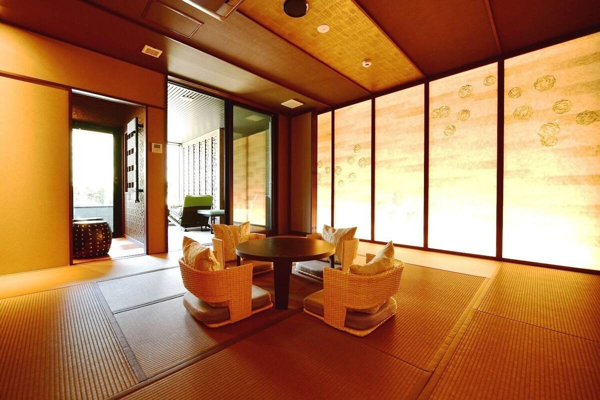 Um quarto japonês tradicional com tatames, uma mesa baixa e cadeiras de fibra natural.