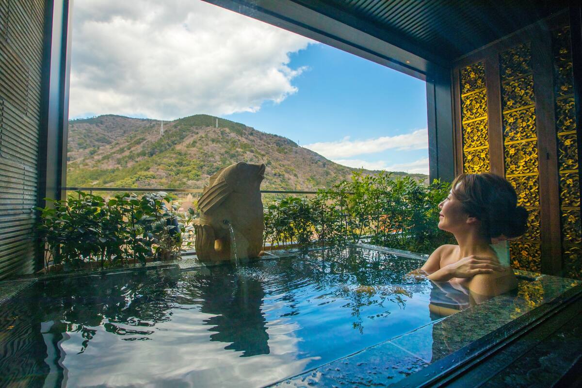 Mulher em banheira de hidromassagem com vista para a montanha.