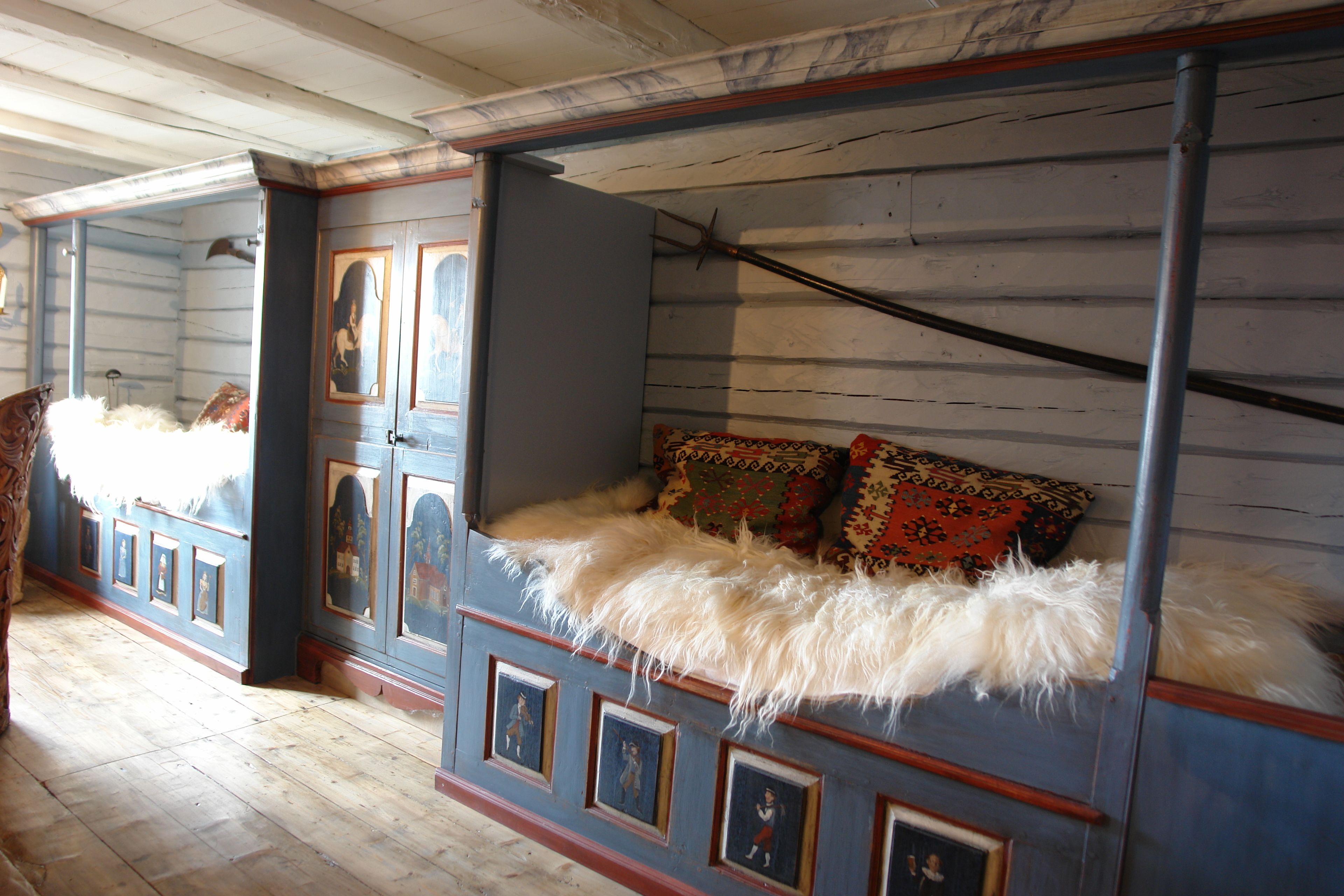 Quarto com um banco de madeira, quadros nas paredes e um cobertor de pele.
